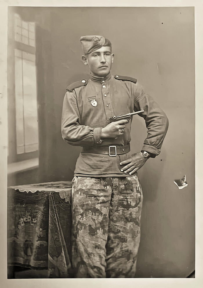 A Soviet Soldier, standing proudly with a trophied Luger in hand, and ...