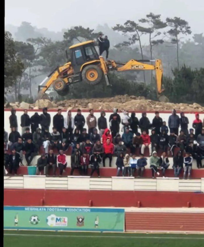 Football fans park JCB outside the stadium to stand atop and watch a ...