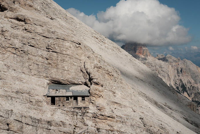 Alpine shelter, built into the side of a vertical mountain peak on ...