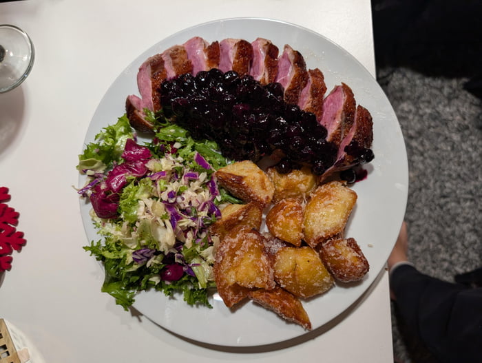Muscovy duck with blueberry sauce, glass roast potatoes and leafs and ...
