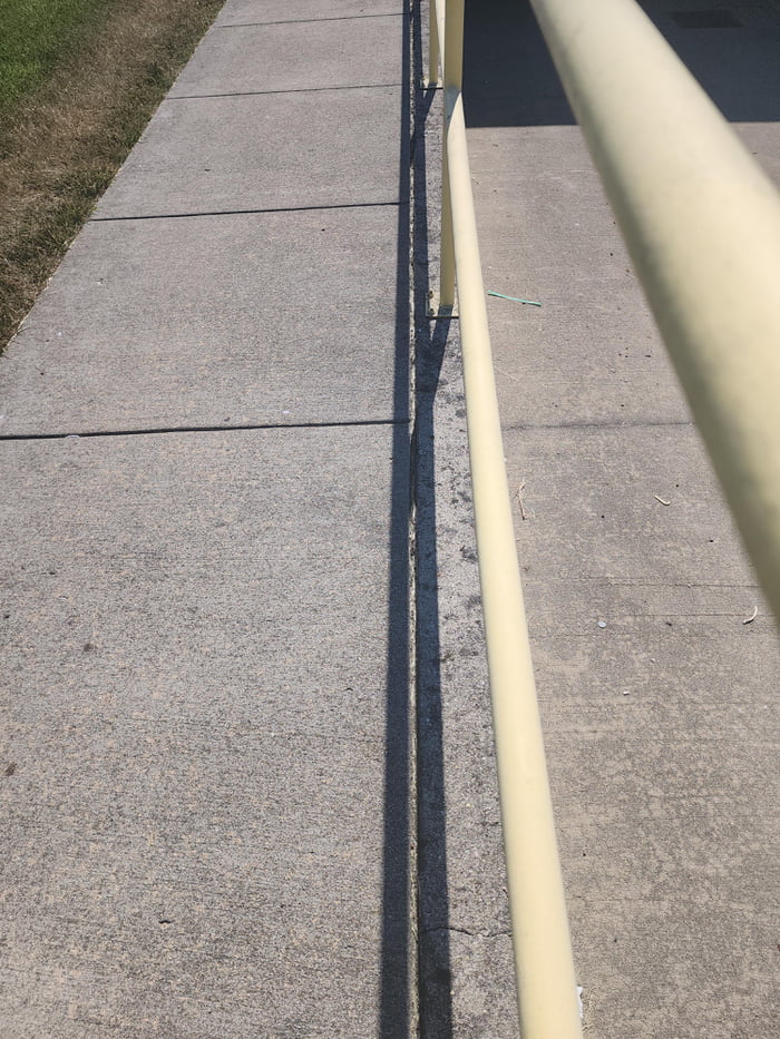 Shadow on this railing perfectly bordered the gap in sidewalk and ...