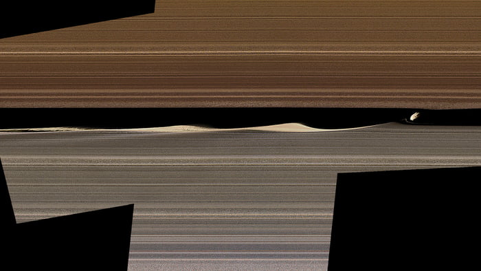 Saturn's moon Daphnis orbits in a gap between two rings, stirring up ...