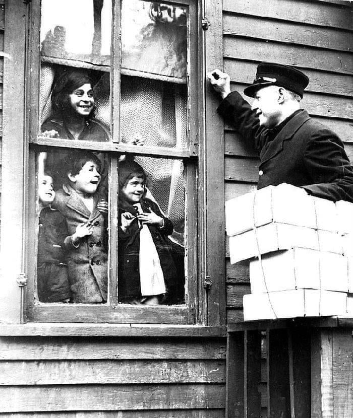 Children smile out a window as donated Christmas presents are delivered ...