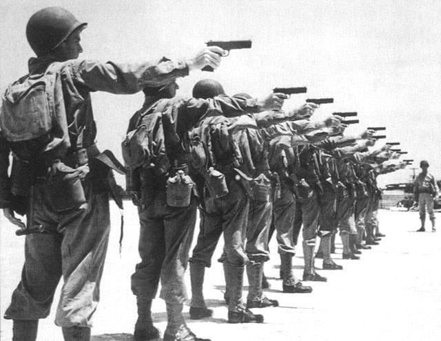 US troops in basic training, practicing their aim with the M1911 handgun at a firing range (1943 ...
