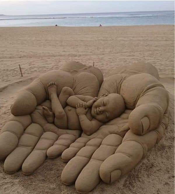 This beautiful sand sculpture of hands carrying a baby. - 9GAG