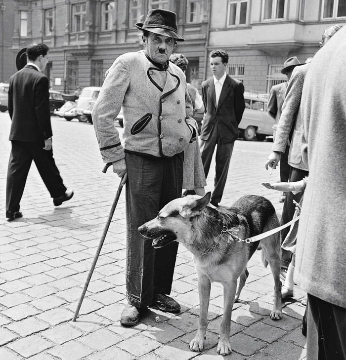 A man with a toothbrush moustache standing next to a German shepherd ...