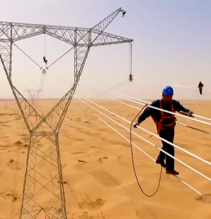 Lineworkers on a 100kv ac powerline, pylons are 100 meters tall. - 9GAG