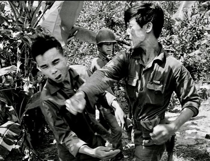 A South Vietnamese soldier punches a captured Viet Cong guerrilla ...
